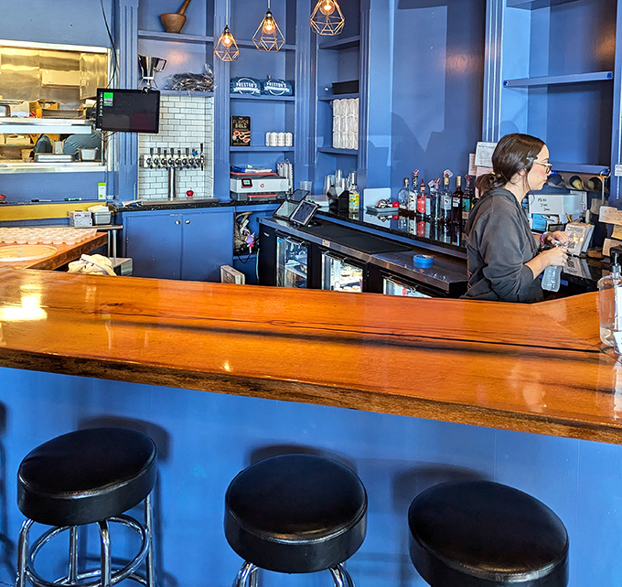 The bar area combines warm wood with cool blue, creating the ideal backdrop for serious burger contemplation and optional beverage pairings.