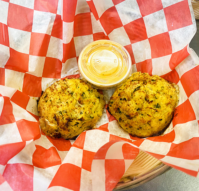 Golden-brown crab cakes nestled in their checkered cradle. These seasoned spheres of crabby goodness are the handheld heroes of the seafood world.