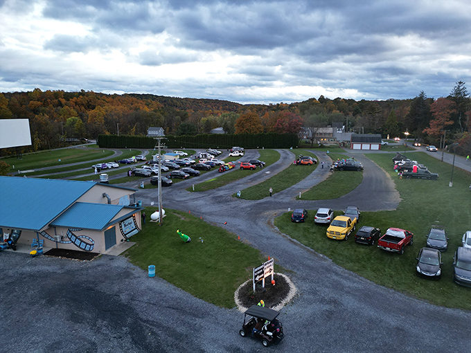Autumn colors frame the drive-in experience as cars settle in for an evening show. The hillside location offers natural stadium-style viewing.