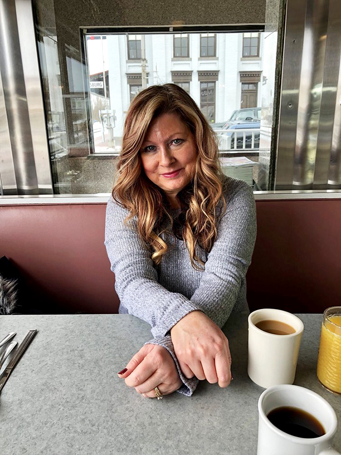 The image shows a patron enjoying the diner experience, where conversations flow as freely as the coffee refills.