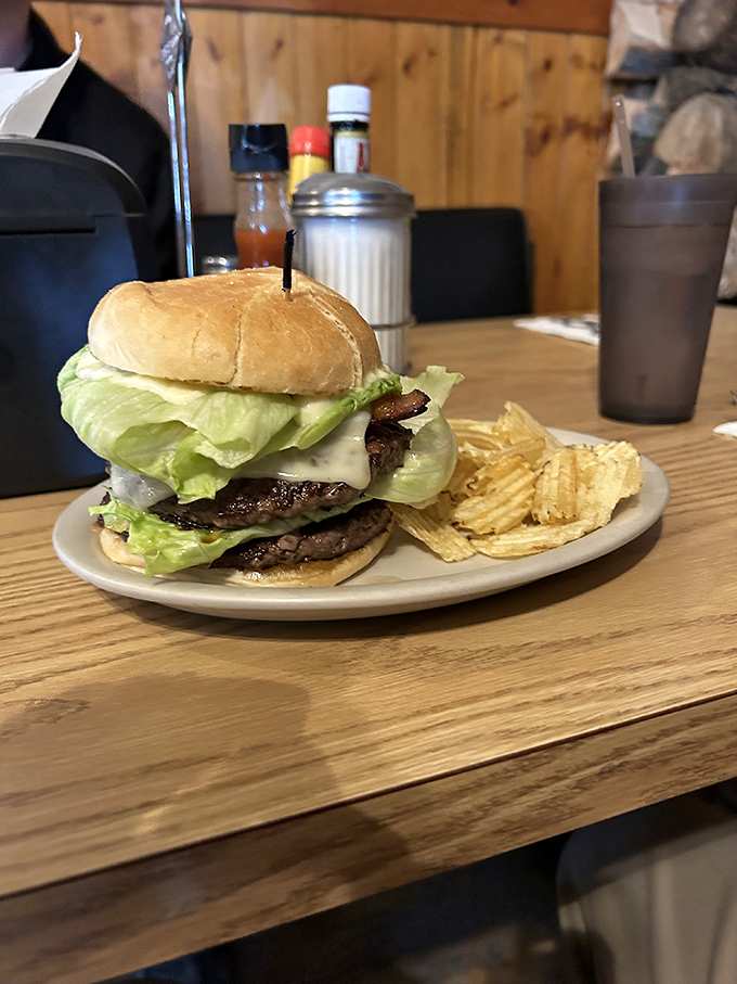 A burger that requires a game plan before the first bite, stacked tall enough to make you wonder if your jaw will unhinge like a snake's.