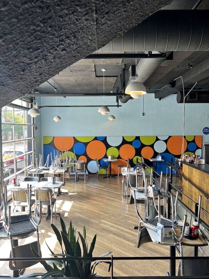 The playful polka dot wall brings a pop of color to this modern space, where breakfast dreams come true under industrial-chic lighting.