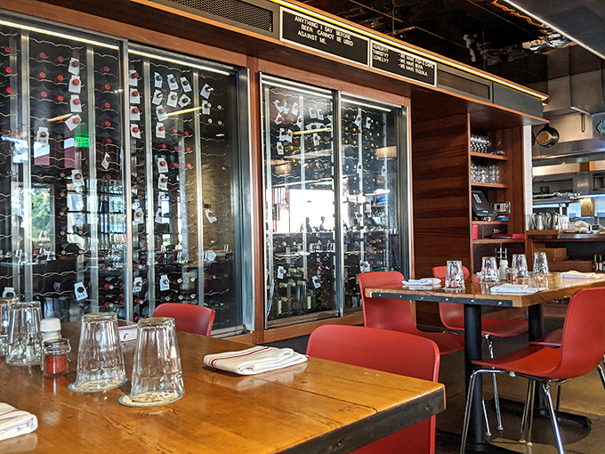 The warm wooden tables against those bright red chairs create the perfect stage for seafood drama. That wine display isn't just storage&mdash;it's a promise.