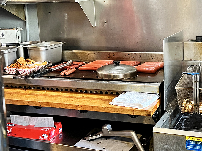 The sacred flat-top grill where hot dog magic happens. Those sizzling franks are getting the spa treatment before their grand entrance on your plate.