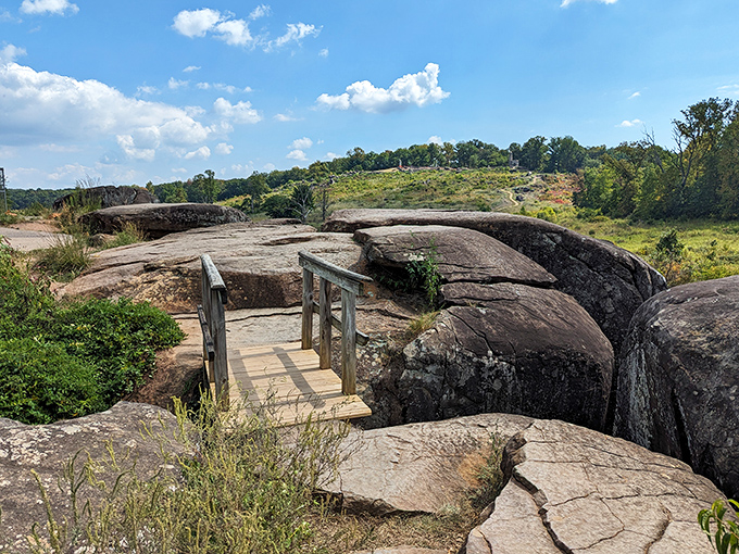 A humble wooden bridge connects massive stone formations, like a comma in nature's epic geological sentence that's been millions of years in the writing.