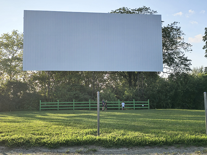 The massive white screen stands sentinel against green fields, waiting for darkness to reveal its stories. 