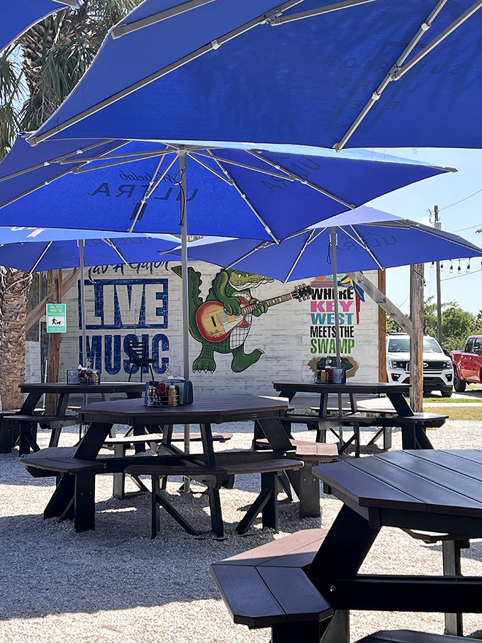 Blue umbrellas shield patrons from the Florida sun while a guitar-wielding gator on the wall reminds you this ain't your average patio.