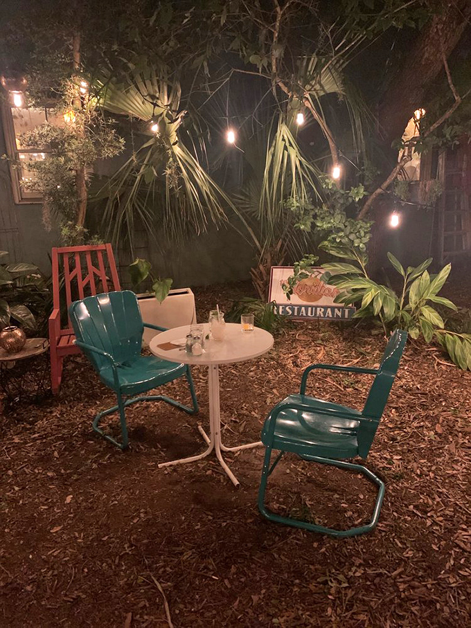 The outdoor seating area transforms into a magical garden at night, string lights twinkling above vintage metal chairs like fireflies.