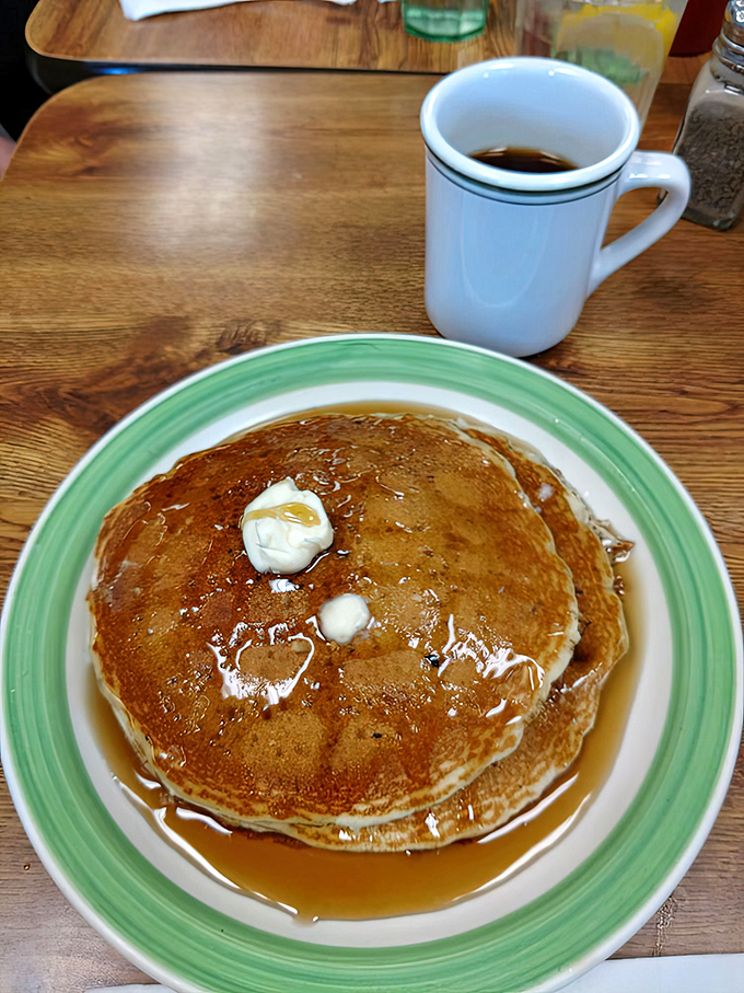 Pancakes that look like they're auditioning for a breakfast commercial, complete with melting butter and syrup rivers creating delicious amber pools.