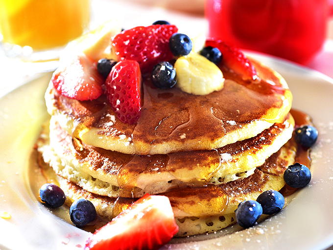 Pancakes stacked like golden discs of joy, fruit scattered with artistic abandon &ndash; breakfast or edible modern art? You decide.