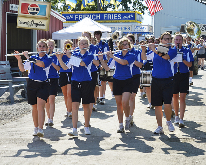 The marching band brings that quintessential small-town parade energy, where every parent is convinced their child is the only one playing the right notes.