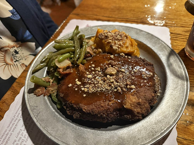 The pork chop arrives glistening with savory gravy and topped with crushed nuts. Those green beans aren't just a side&mdash;they're vegetables with purpose.