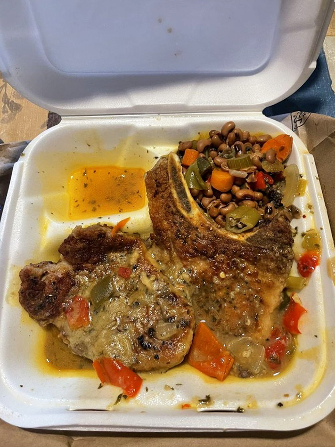 Pork chops swimming in savory gravy alongside black-eyed peas and vegetables – proof that some of life's greatest pleasures come in simple styrofoam containers.