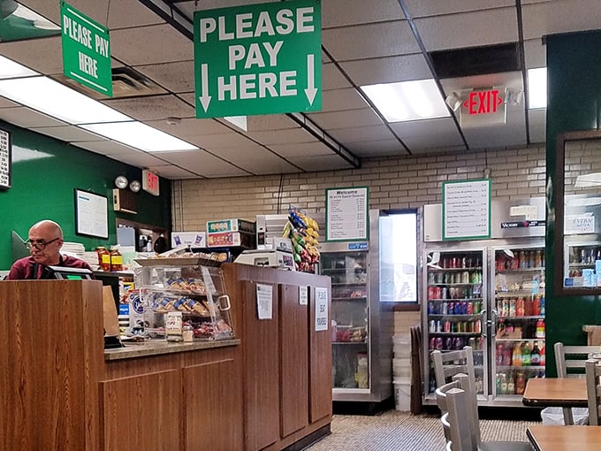 The "Please Pay Here" sign hangs above the register&mdash;a reminder of simpler times when transactions were straightforward and desserts waited in glass cases.