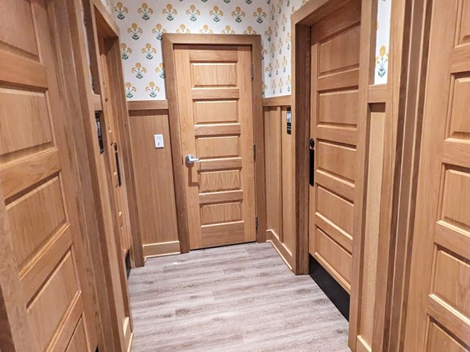 Even the restroom hallway has personality with floral wallpaper and wooden doors that look like they belong in a fancy farmhouse, not a restaurant bathroom.