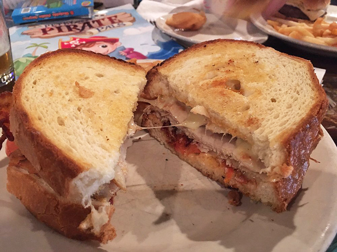 This sandwich, cut in half to reveal its secrets, is like a cross-section of happiness. Melty cheese meets savory fillings in bread toasted to golden perfection.