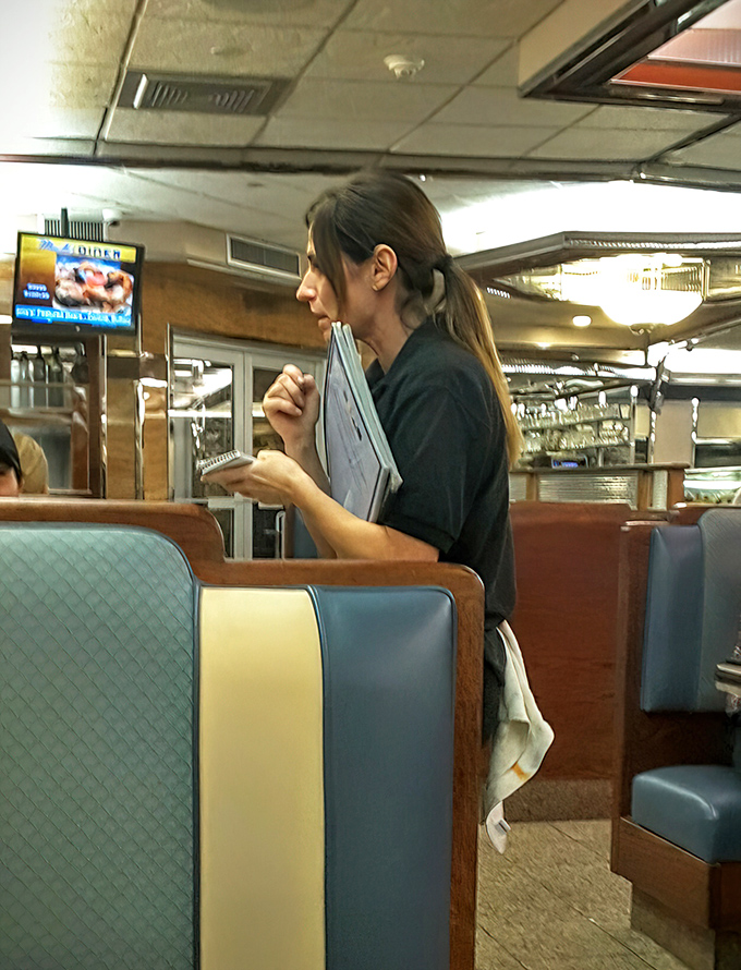 The waitstaff moves with practiced efficiency&mdash;order pads at the ready, navigating the dance of service that keeps a beloved diner running smoothly.