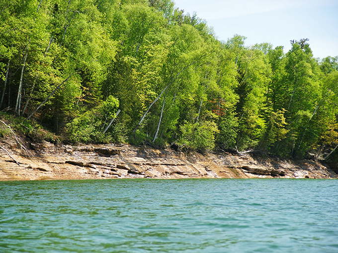 Sandstone cliffs meet emerald forest in a perfect marriage of geology and botany, with Lake Superior's impossibly clear waters serving as the wedding photographer.