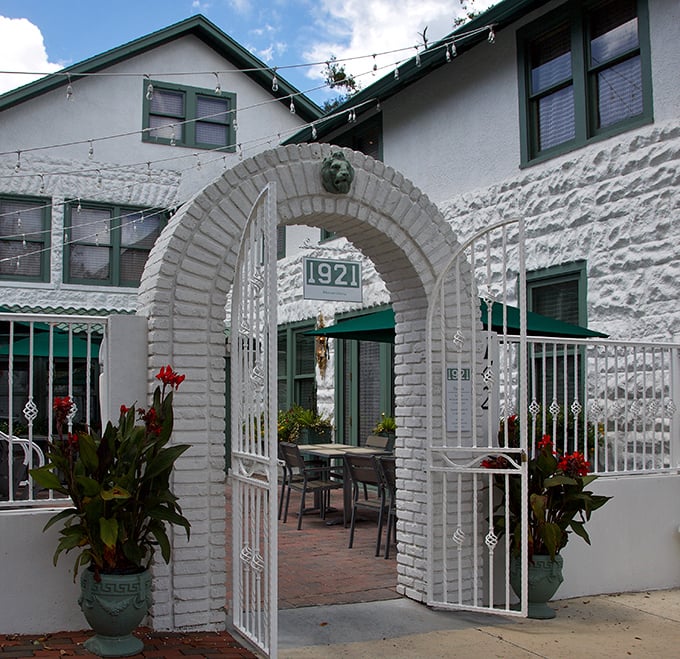1921 Mount Dora's elegant white archway invites you into a courtyard dining experience that feels both timeless and contemporary.