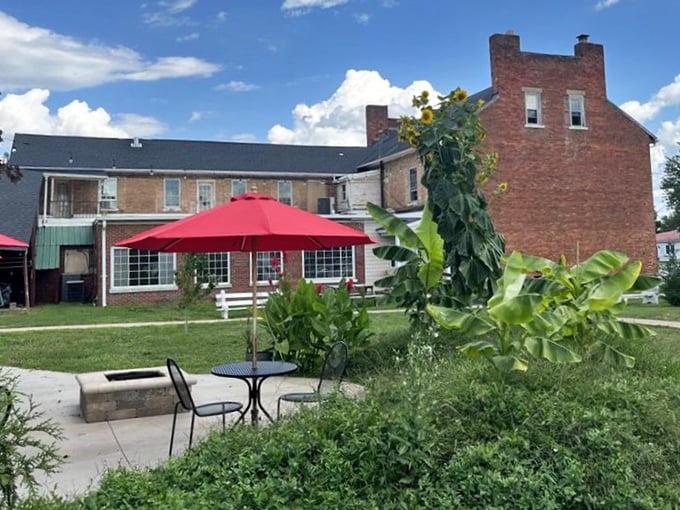 The outdoor seating area offers a peaceful retreat where summer sunflowers stand tall against the tavern's sturdy brick backdrop. 
