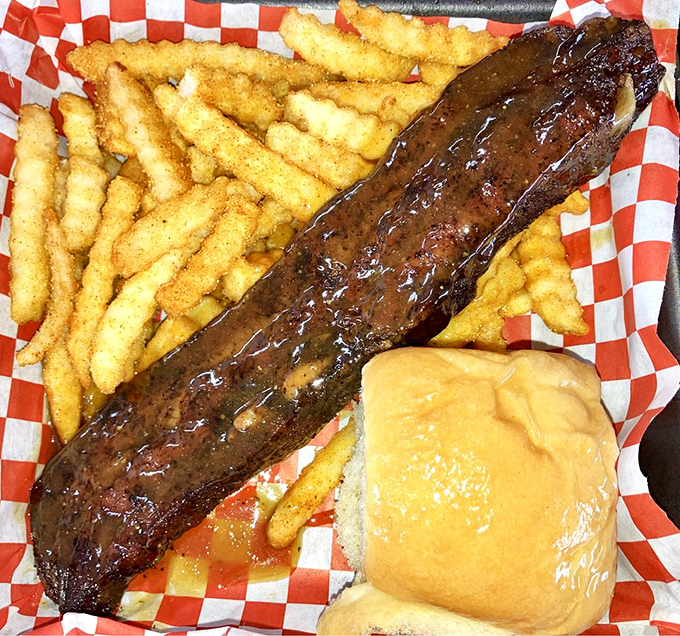 A rib that looks like it should be in a barbecue museum, glistening with sauce and flanked by golden fries and a roll for sauce-sopping duty.
