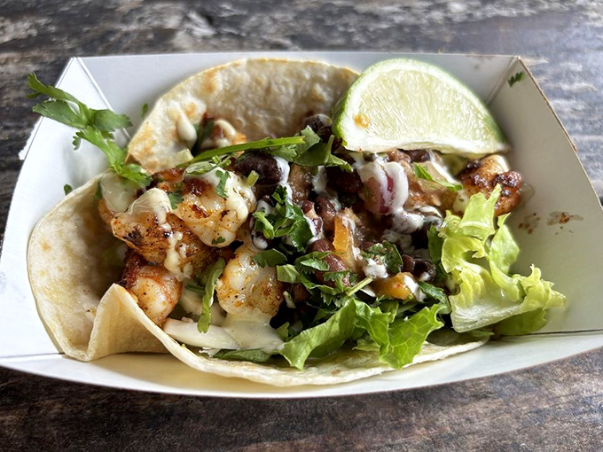 A shrimp taco that's dressed better than most people at the beach—fresh greens, perfectly seasoned shrimp, and a squeeze of lime for that perfect finish.