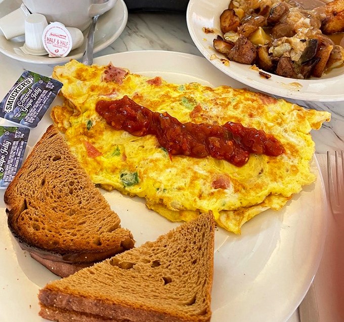 An omelet that's seen things—specifically, ham, cheese, and vegetables—before being blanketed in salsa and paired with toast soldiers ready for action.