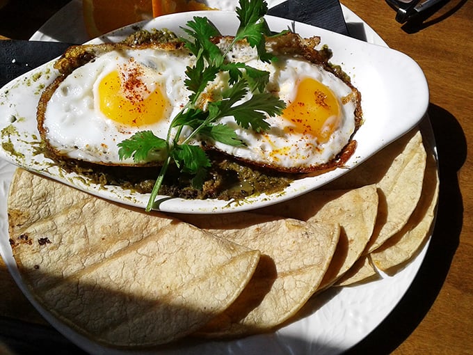 Two sunny-side-up eggs crown this verde masterpiece like royalty, with corn tortillas standing by to ensure not a drop goes to waste.