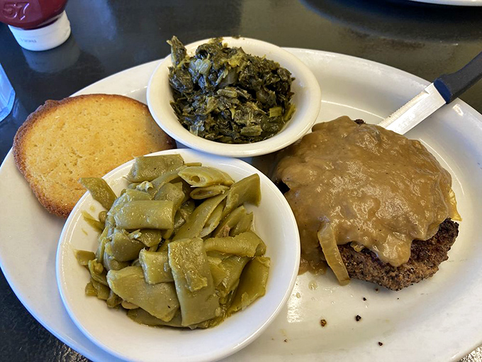 Southern cooking in its glory: chopped steak smothered in gravy with sides of collard greens and green beans. This isn't food; it's a hug on a plate.