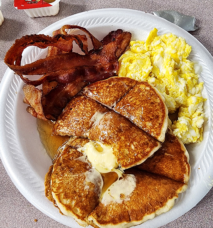 Breakfast perfection: golden pancakes with melting butter, eggs that know exactly what they're doing, and bacon that makes you question all other bacon.