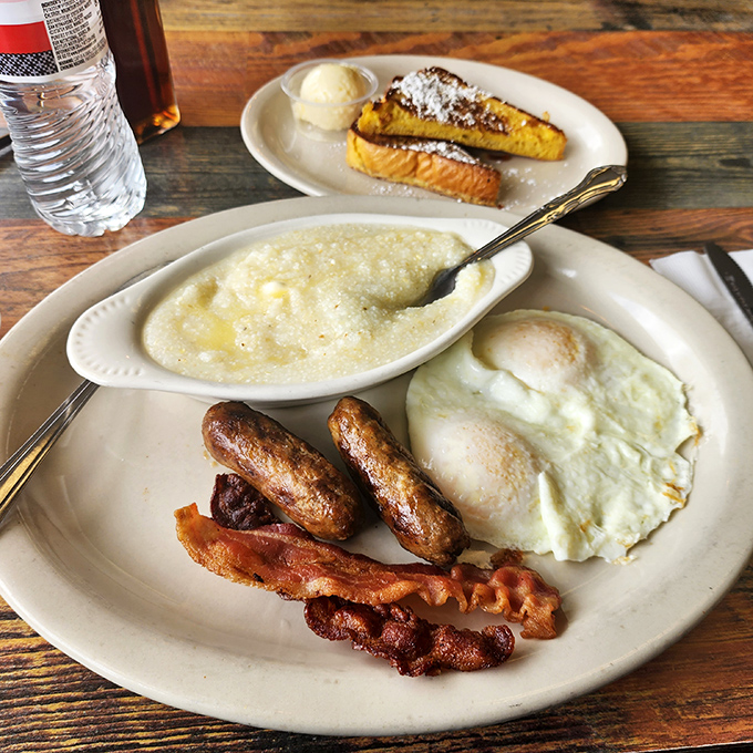 The classic breakfast plate speaks a universal language: perfectly cooked eggs, sausage links standing at attention, and grits that would make a Southerner nod approvingly.