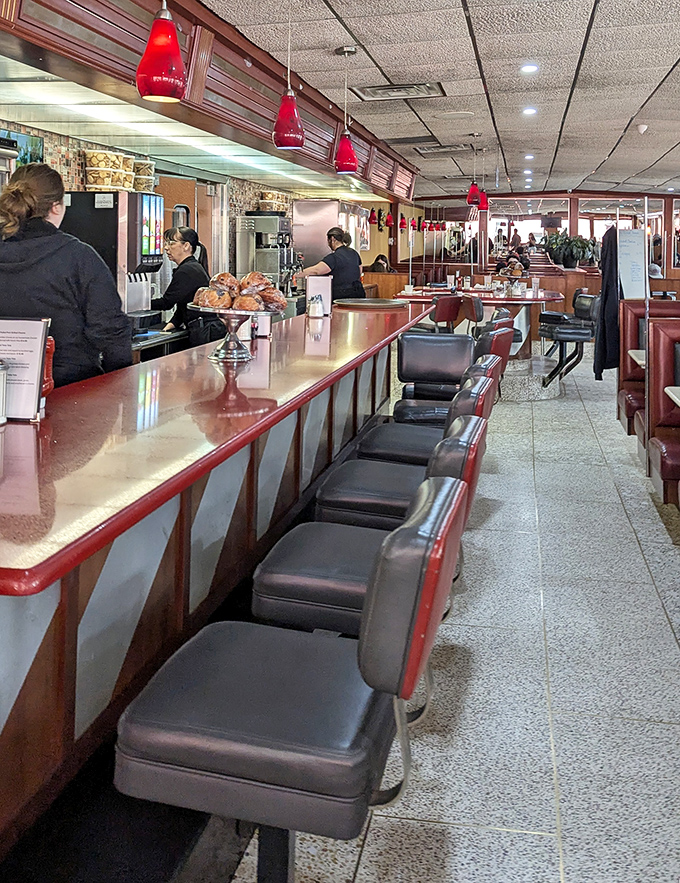 The counter seats&mdash;where solo diners become regulars and servers become therapists. Red pendant lights add that classic diner glow.