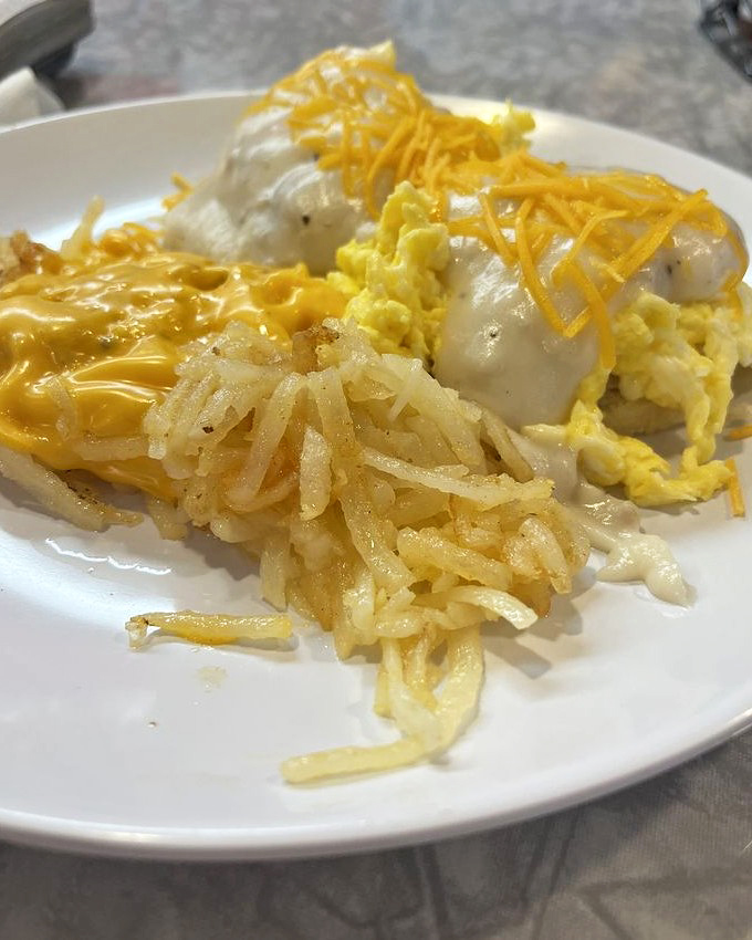 Country gravy cascading over eggs and hash browns creates a breakfast landscape worth exploring with every bite of your fork.