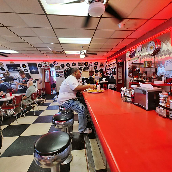 The glowing neon sign illuminates the pass-through window where breakfast dreams are born. The kitchen ballet continues all morning long.