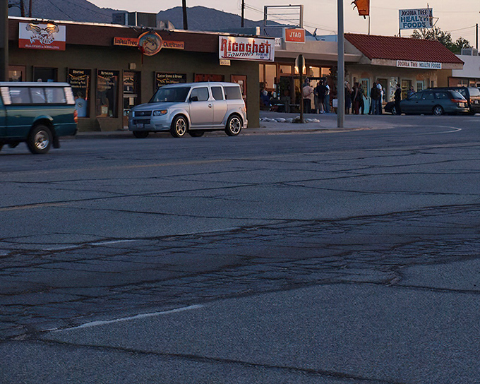 As evening approaches, Joshua Tree's small businesses light up the desert night. The mountains provide a dramatic backdrop to small-town charm.