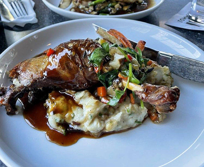 Duck confit so tender it practically falls apart at first glance, swimming in rich, glossy sauce.