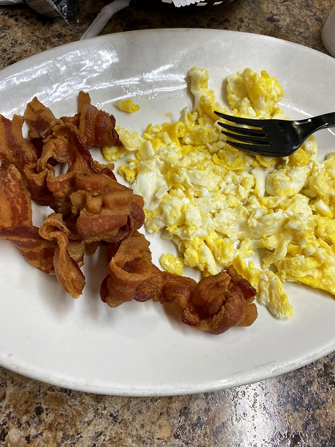 Breakfast fundamentals executed with precision&mdash;eggs scrambled to fluffy perfection alongside bacon that's achieved that mythical balance between crisp and chewy.