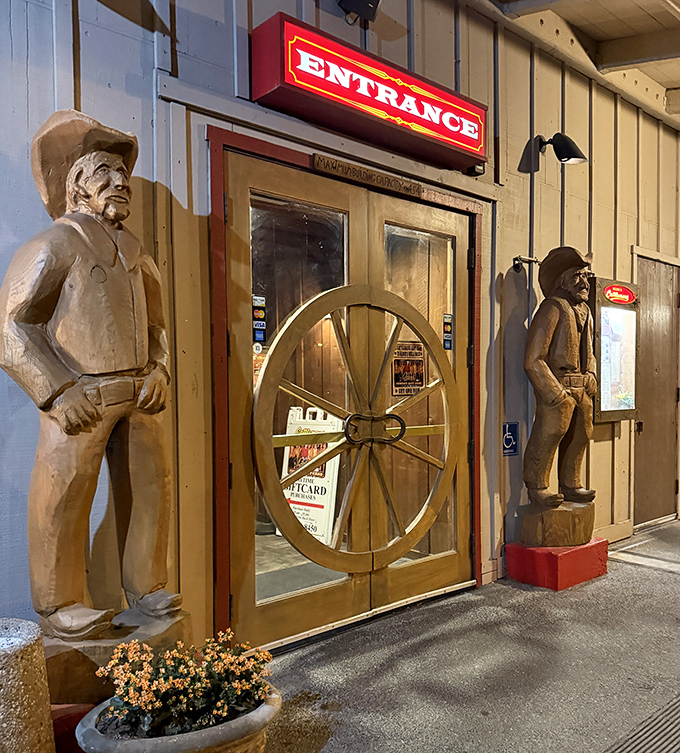 Wooden cowboy sentinels guard the entrance, silently judging if you're worthy of the beef bounty that awaits inside.
