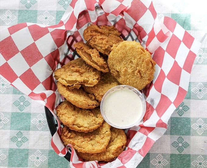 Fried green tomatoes stacked like golden coins, with dipping sauce that makes you wonder why we ever eat tomatoes ripe.