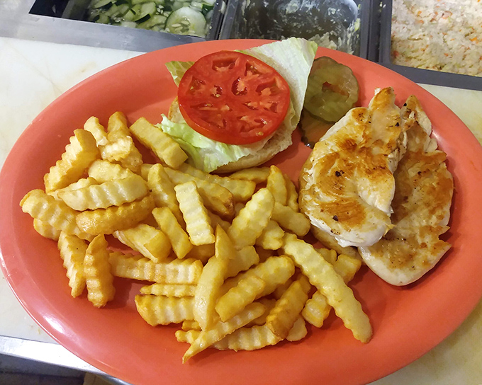 The grilled chicken sandwich that proves simple food done right is culinary poetry. Those crinkle-cut fries are the supporting actors who steal the scene.