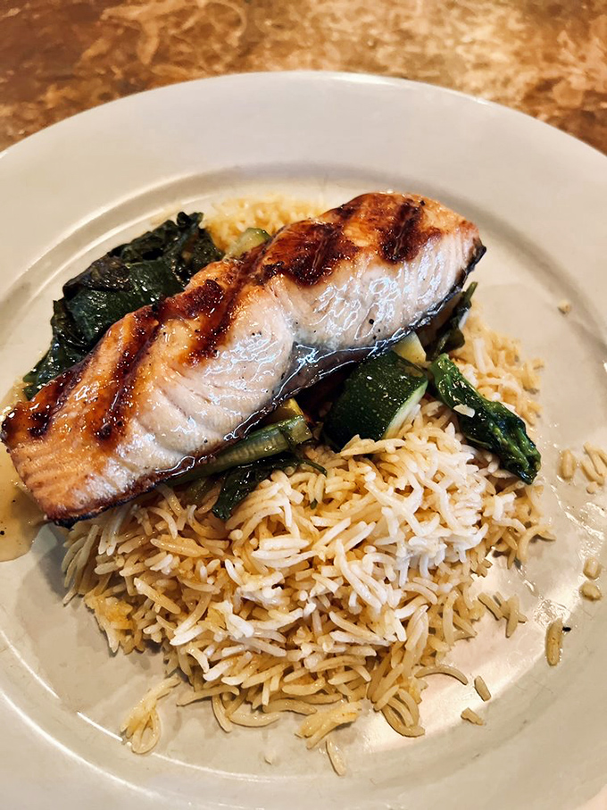 Perfectly grilled salmon resting on a bed of rice and vegetables &ndash; proof that sometimes the simplest preparations yield the most magnificent results.