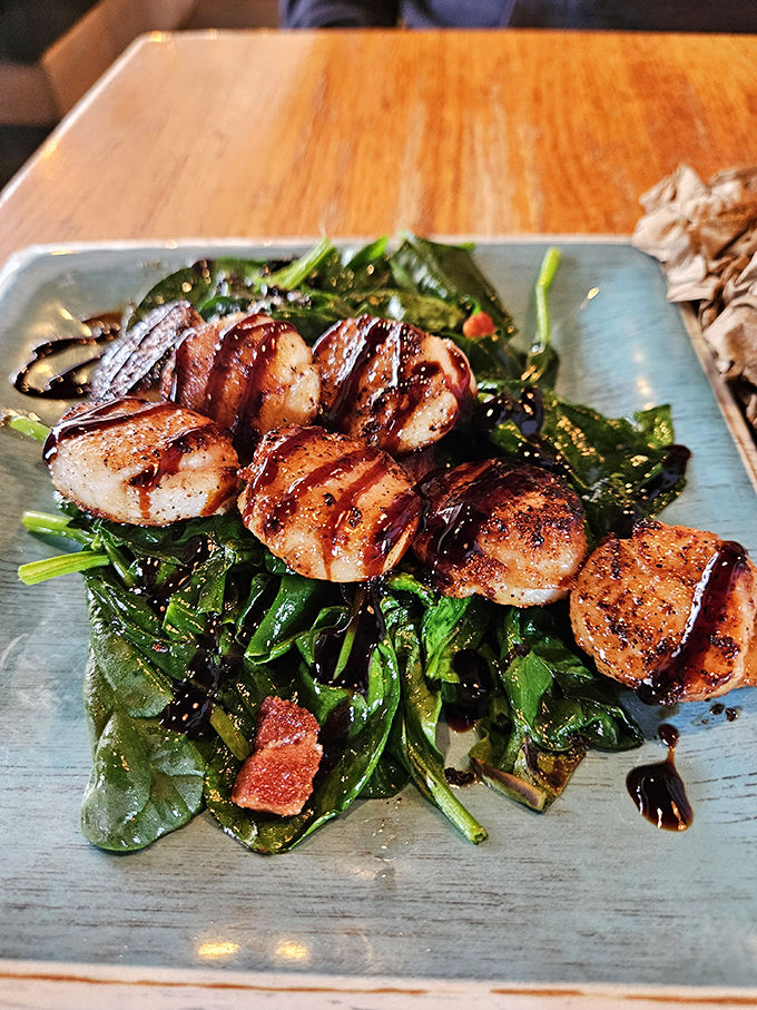 Perfectly seared scallops atop fresh greens&mdash;a dish that showcases the kitchen's finesse beyond frying. Those caramelized edges contain universes of flavor.