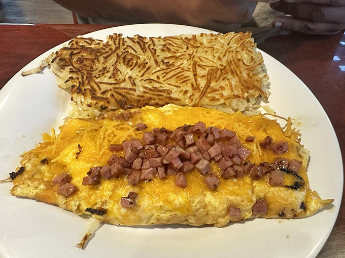 An omelet that knows how to dress for breakfast &ndash; golden cheese blanket, ham confetti, and a hash brown companion that's achieved crispy perfection.
