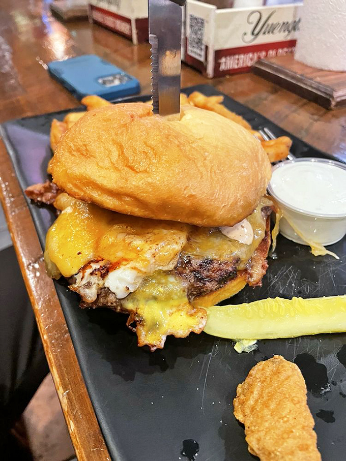 Not your average cheeseburger—this towering creation with melted cheese cascading down the sides practically dares you to unhinge your jaw.