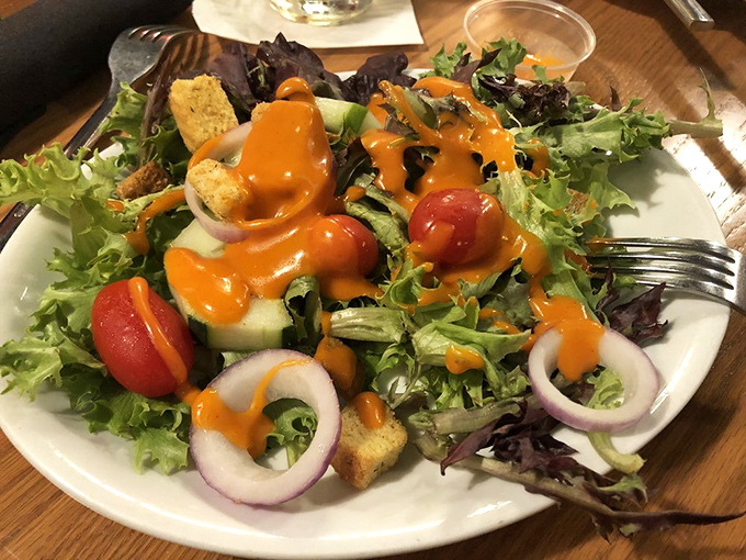 A garden-fresh salad dressed in vibrant orange vinaigrette brings color and crunch to the table—the opening act that deserves its own standing ovation.