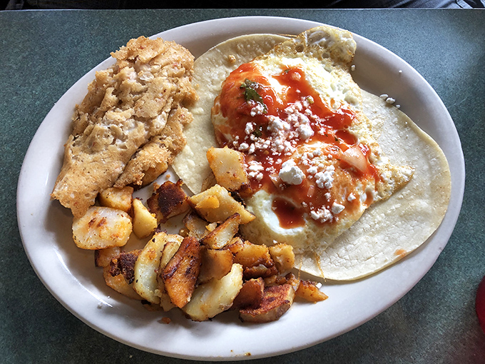 Not your average breakfast plate – this egg-topped creation with home fries proves that morning meals deserve more than mere toast.