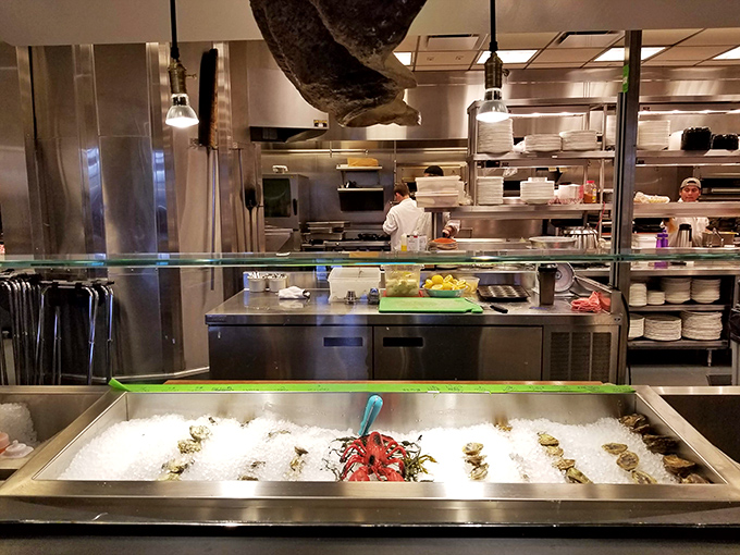 Behind the glass, chefs orchestrate a seafood symphony while fresh catches rest on ice, awaiting their culinary transformation.