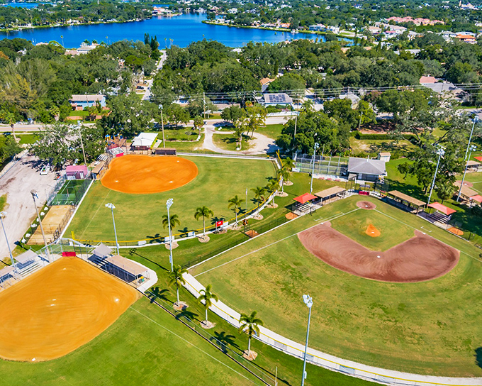Little League fields shimmer under the Florida sun, where community traditions play out against a backdrop of perfect blue waters.