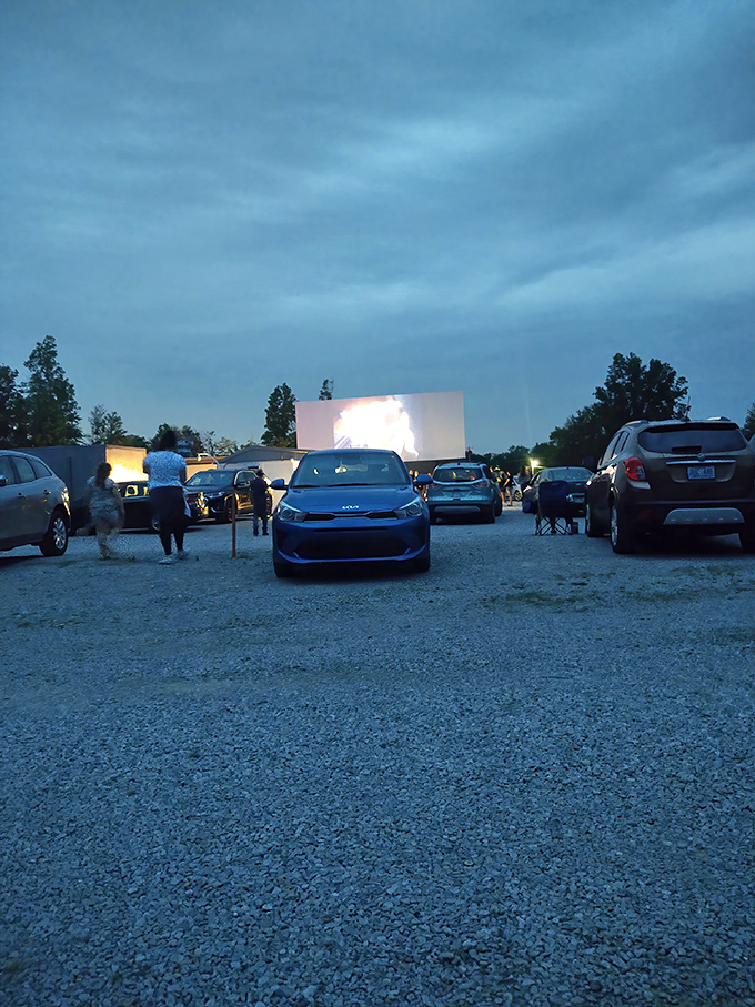As darkness falls, headlights dim and the screen illuminates, transforming a gravel lot into a cathedral of collective imagination.