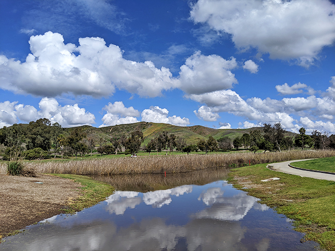 The golf course's pond mirrors perfect clouds while hills rise in the distance. Oceanside's inland beauty offers a different kind of blue than its famous coastline.